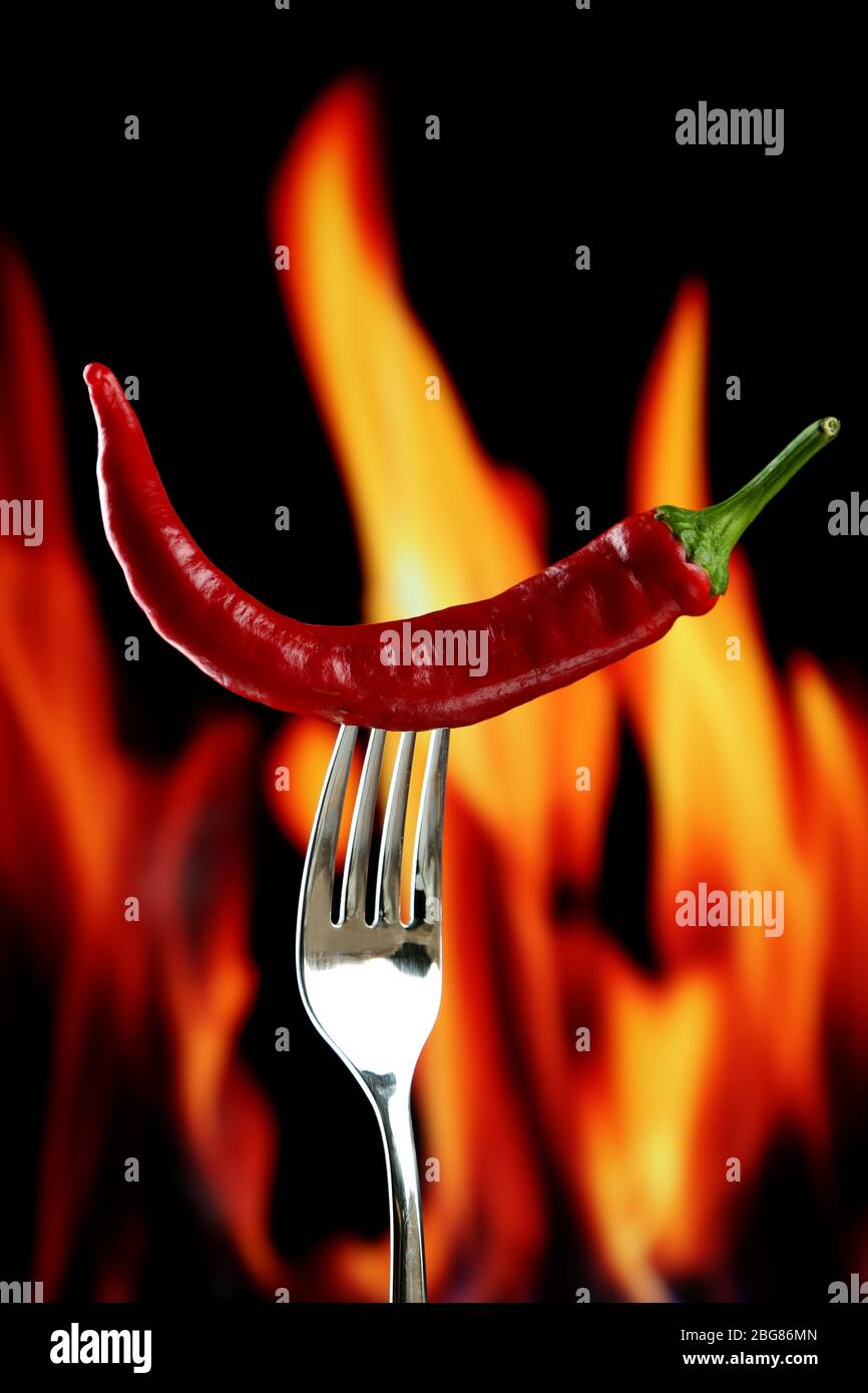Red hot chili pepper on fork, on fire background Stock Photo - Alamy
