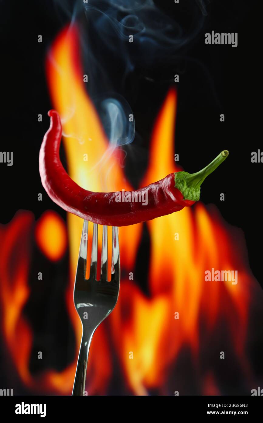 Red hot chili pepper on fork, on fire background Stock Photo - Alamy
