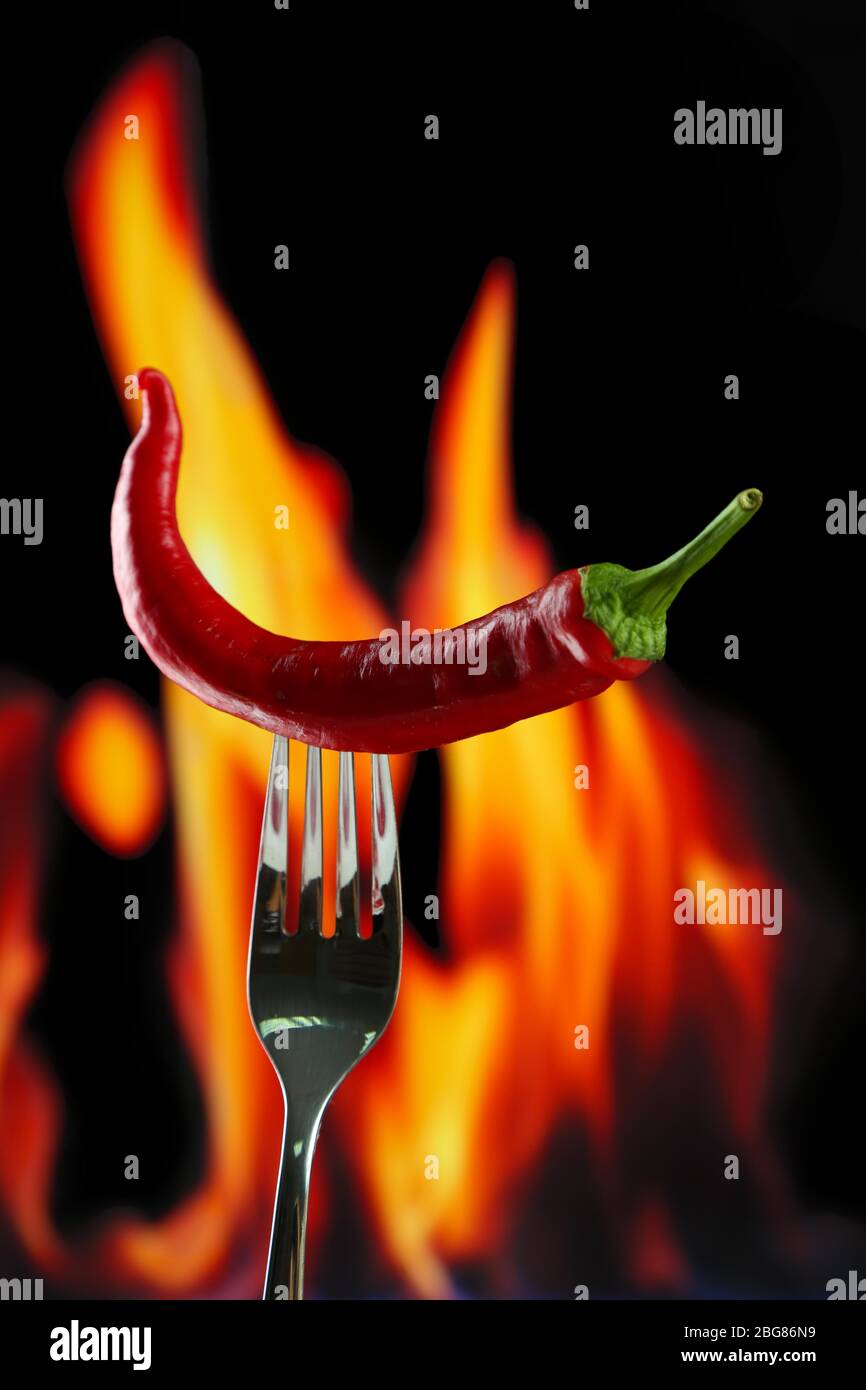 Red hot chili pepper on fork, on fire background Stock Photo - Alamy