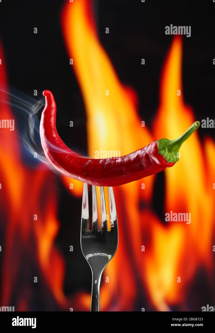 Red hot chili pepper on fork, on fire background Stock Photo - Alamy