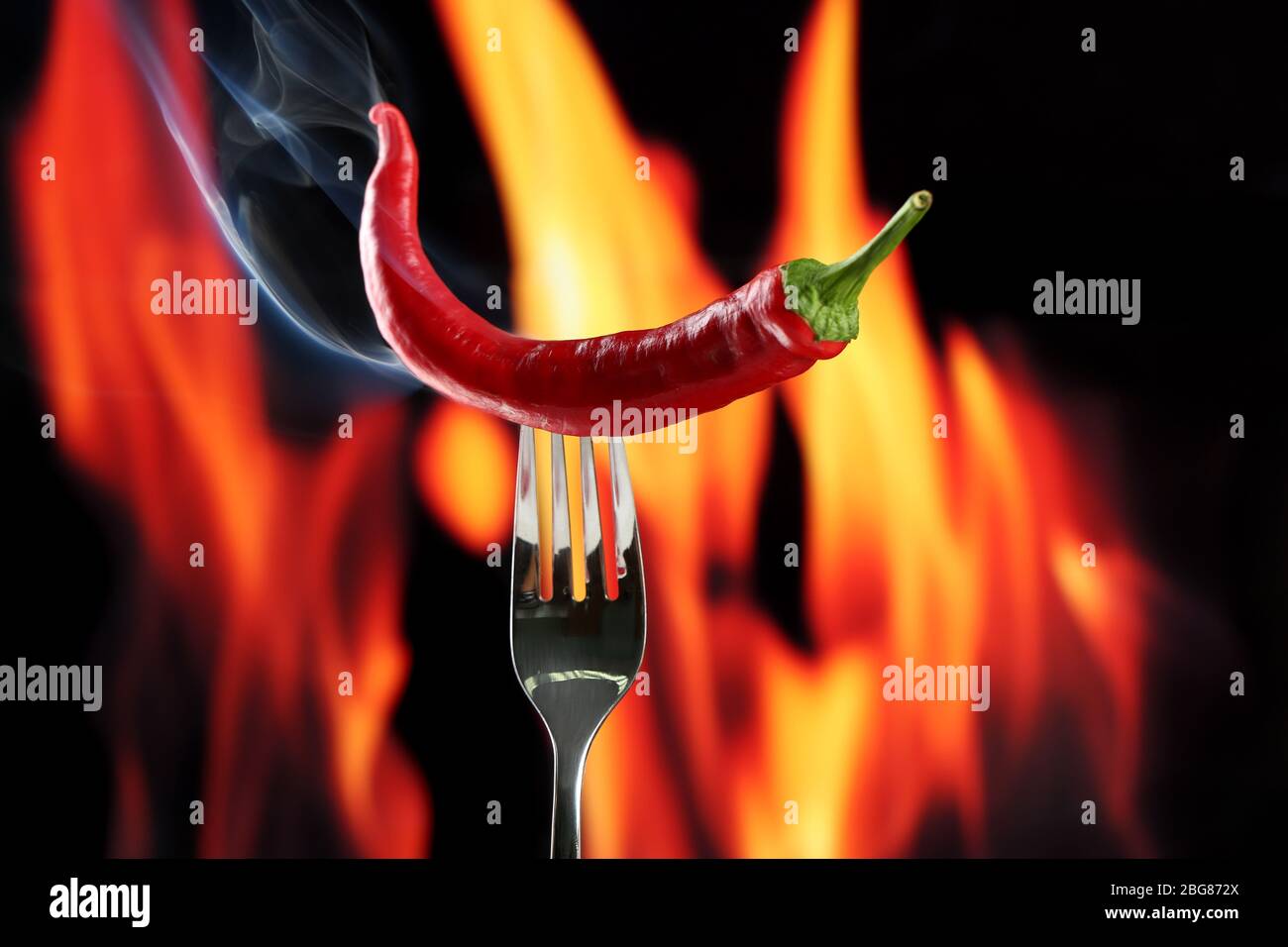 Red hot chili pepper on fork, on fire background Stock Photo - Alamy
