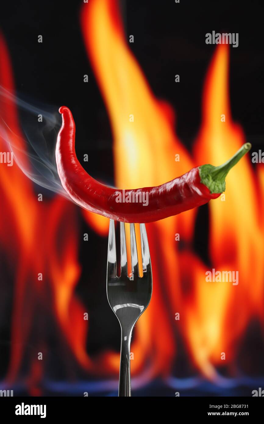 Red hot chili pepper on fork, on fire background Stock Photo - Alamy