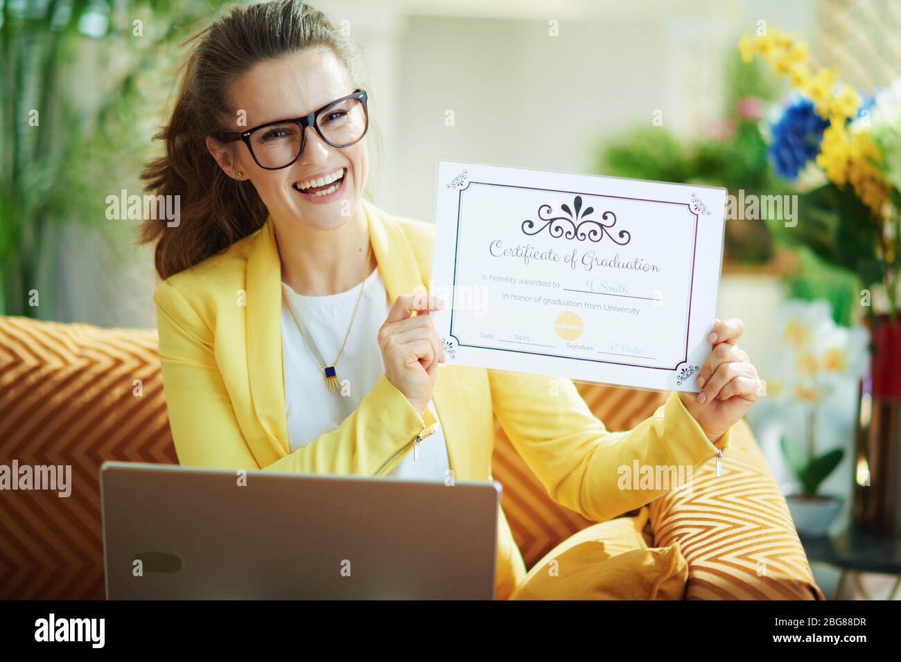 happy stylish female in jeans and yellow jacket with laptop showing ...