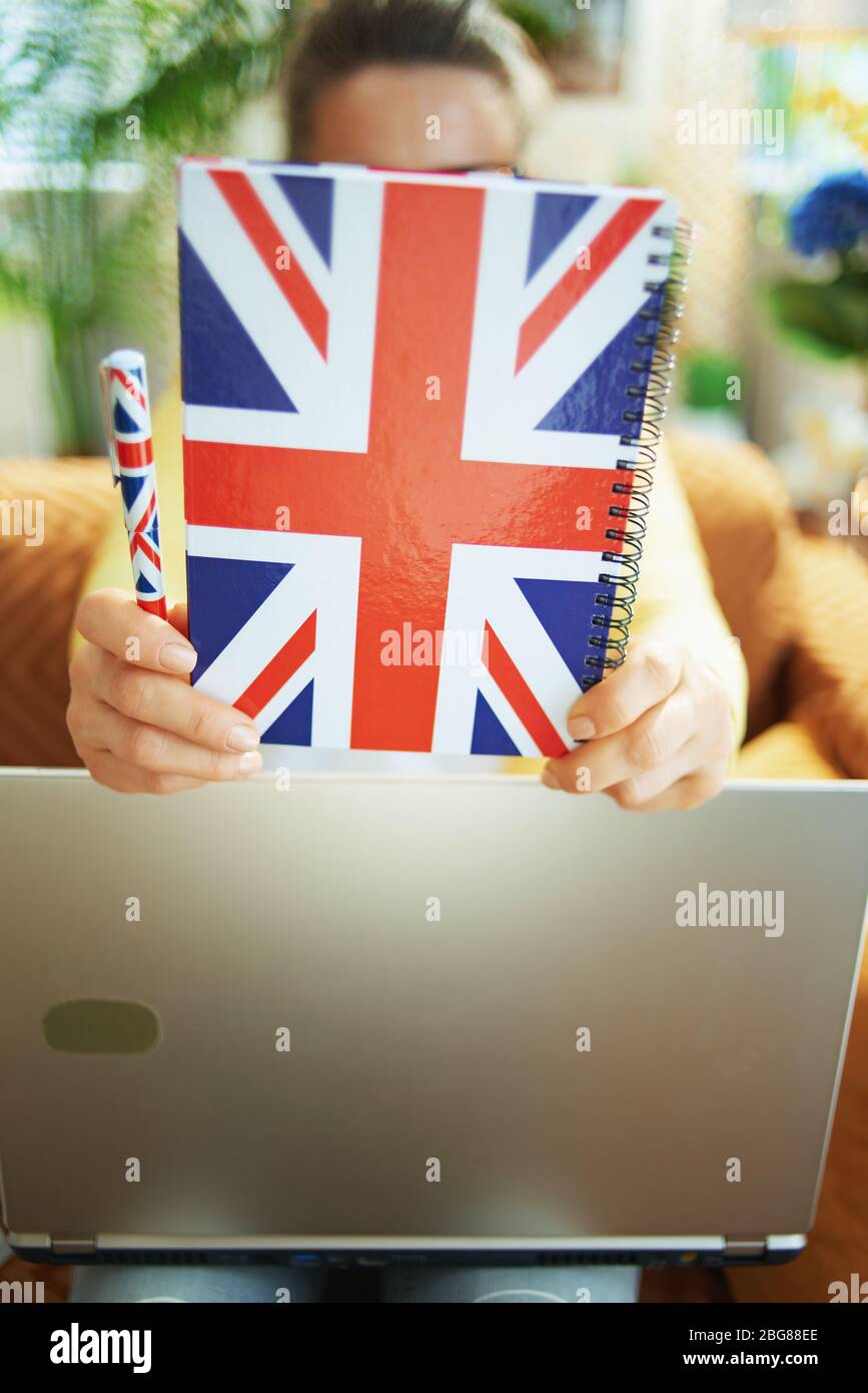 Closeup on learner woman with laptop holding UK flag notebook in the ...