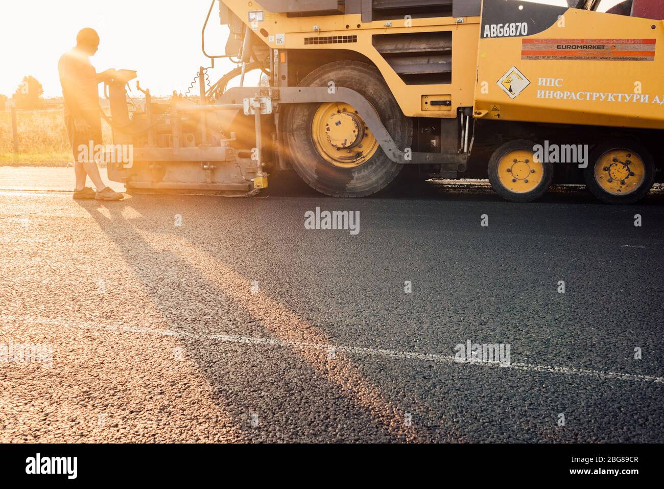 Highway Road worker operating asphalt machine laying new asphalt or ...