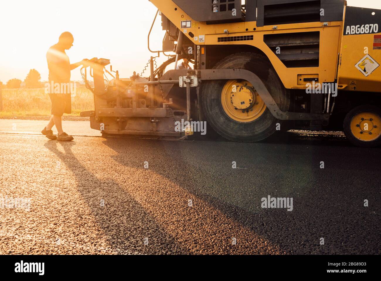 Highway Road worker operating asphalt machine laying new asphalt or ...