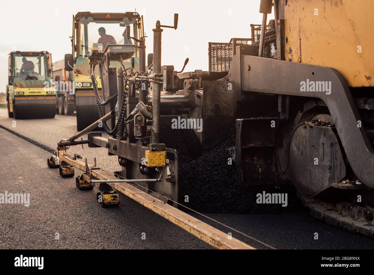 road construction workers operating pavement machine. highway ...