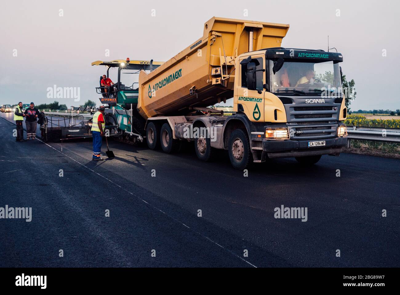 road construction workers operating pavement machine. highway ...
