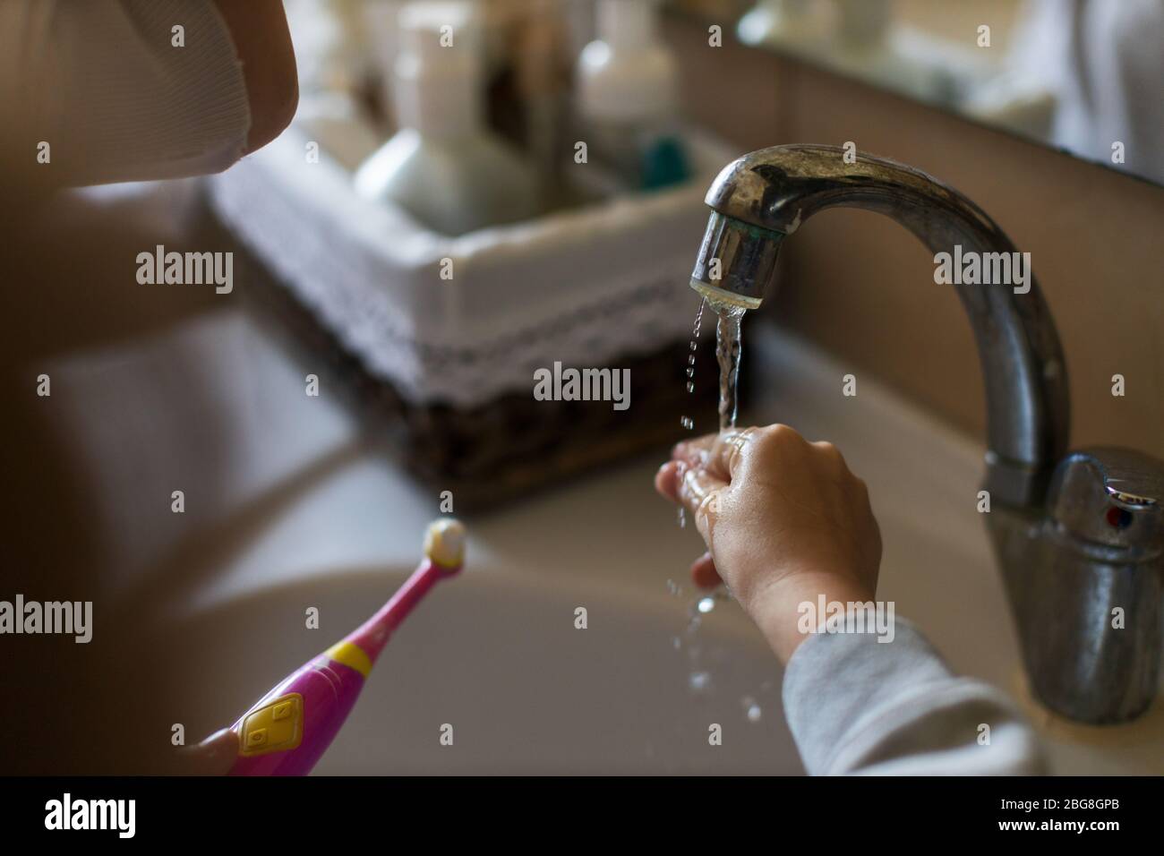 washing the toothbrush under the water flow in the washbasin, morning ...