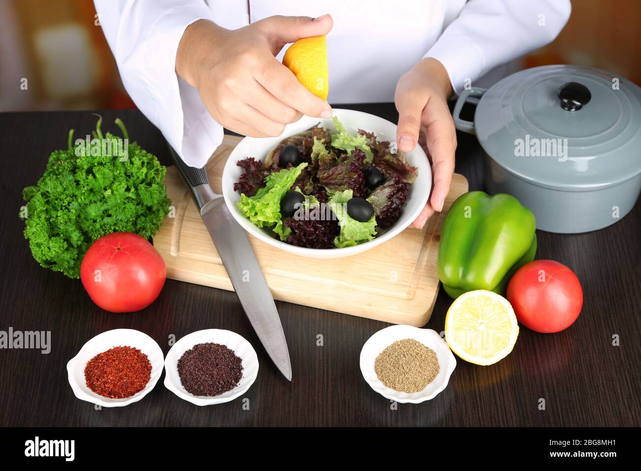 Cook hands squeezing lemon into salad Stock Photo - Alamy