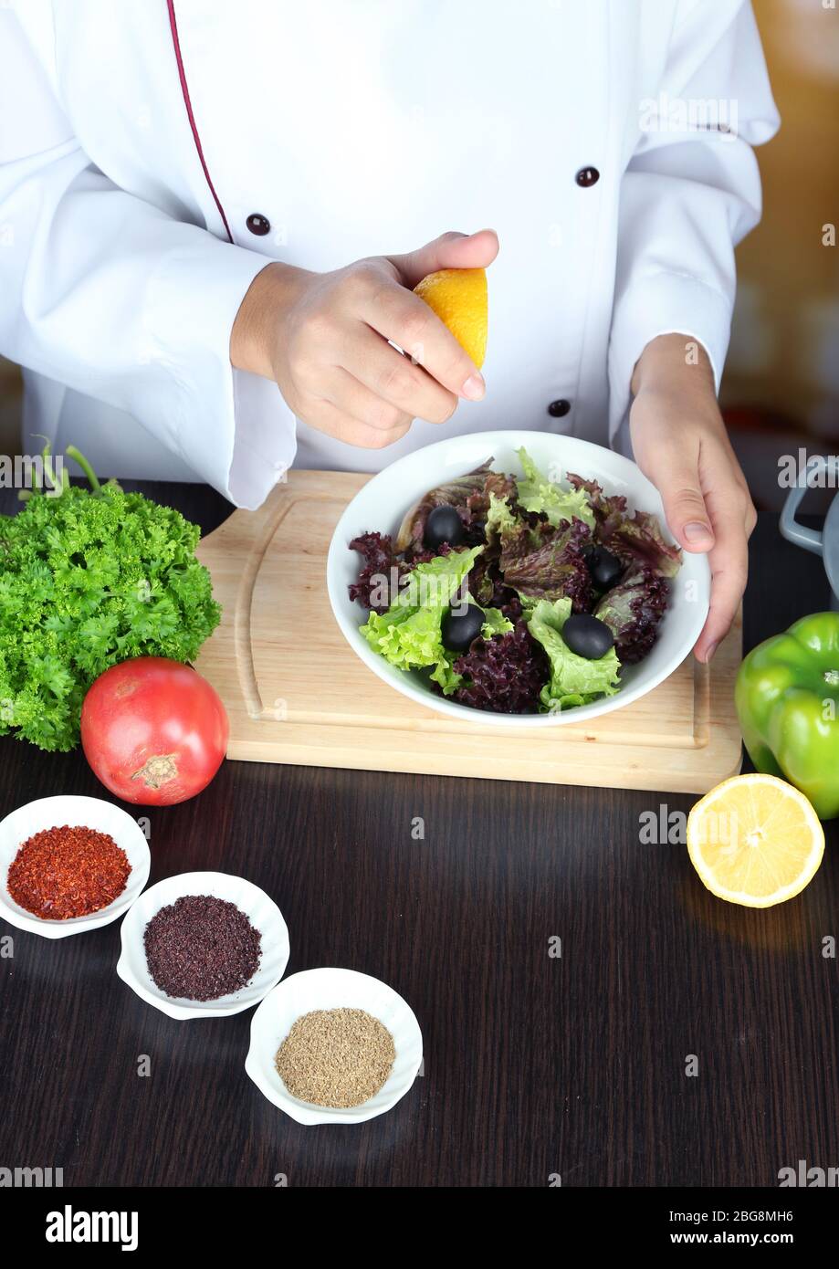 Cook hands squeezing lemon into salad Stock Photo - Alamy