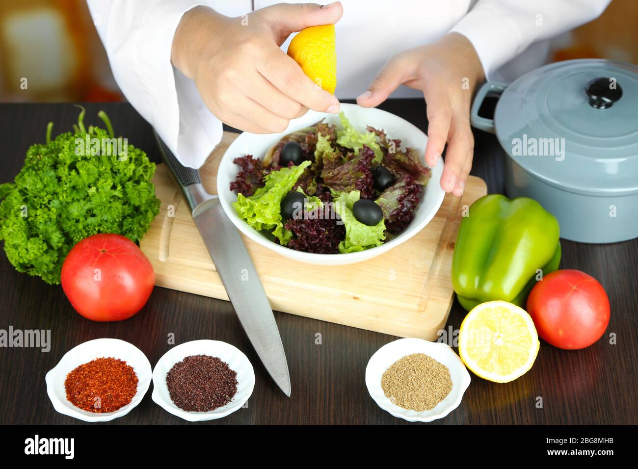 Cook hands squeezing lemon into salad Stock Photo - Alamy