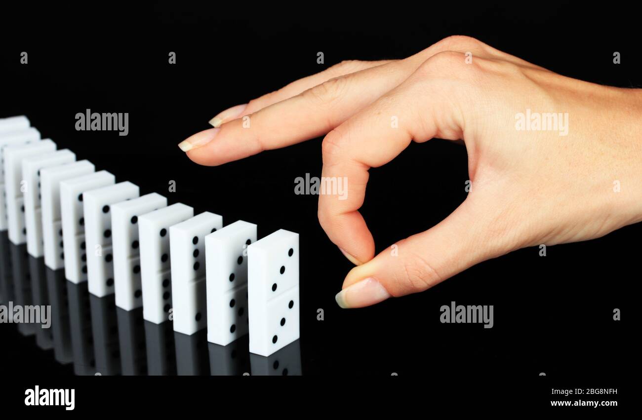 Hand pushing dominoes isolated on black Stock Photo - Alamy