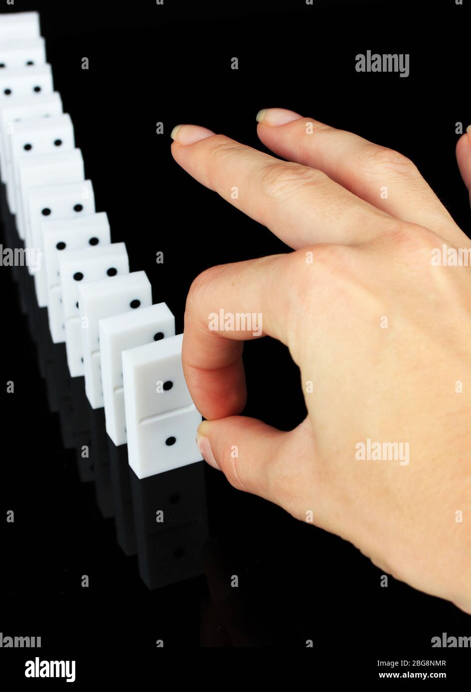 Hand pushing dominoes isolated on black Stock Photo - Alamy