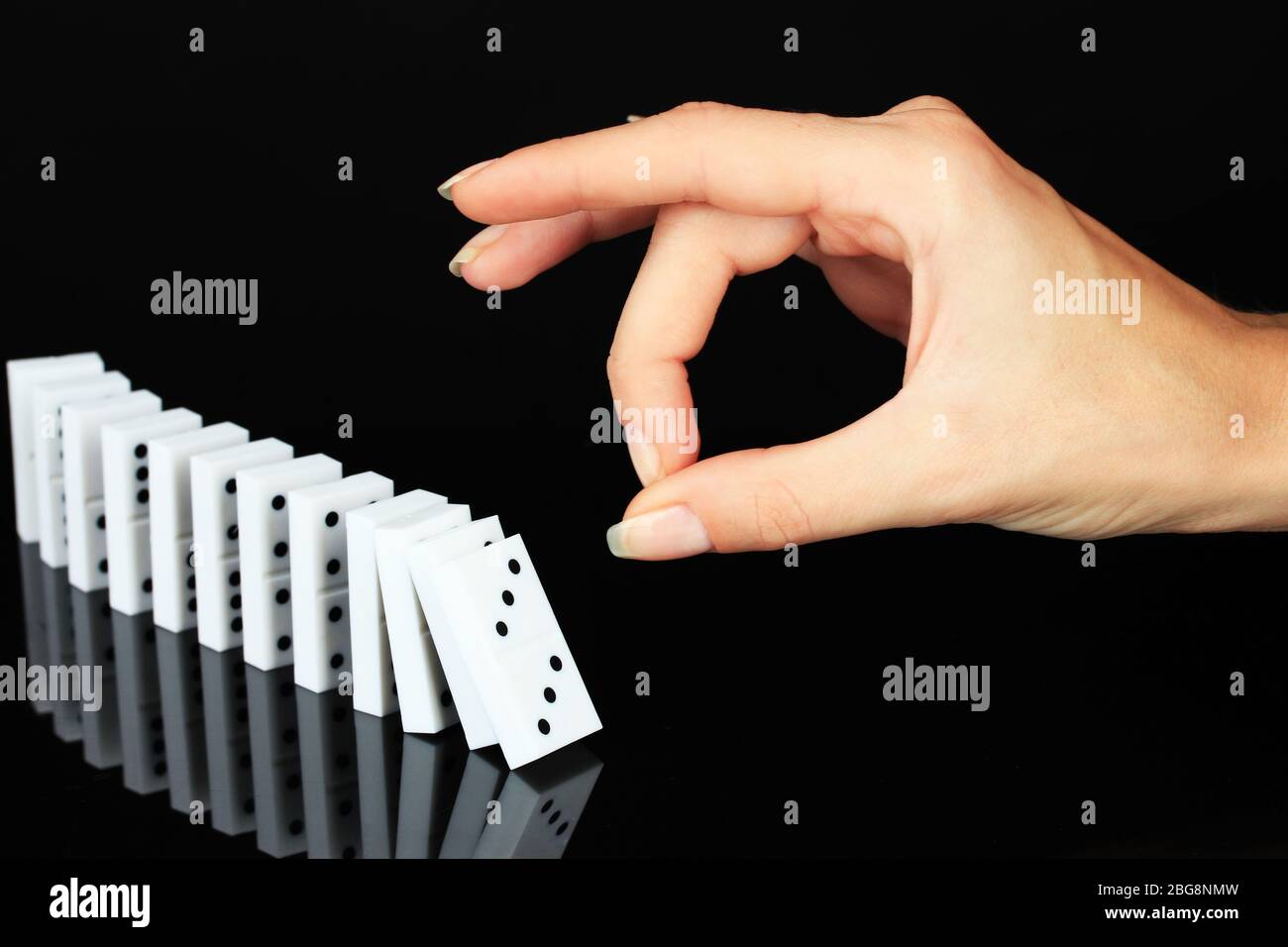 Hand pushing dominoes isolated on black Stock Photo - Alamy