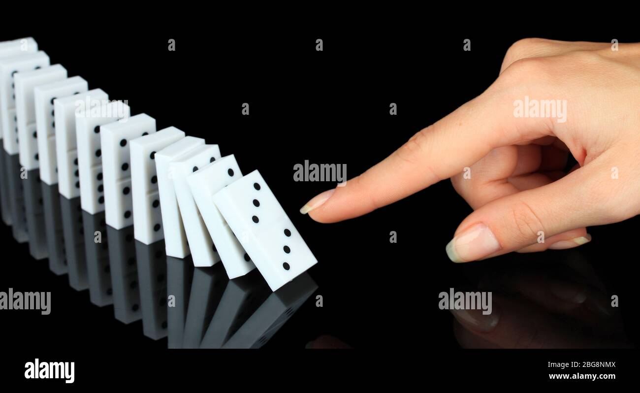 Hand pushing dominoes isolated on black Stock Photo - Alamy