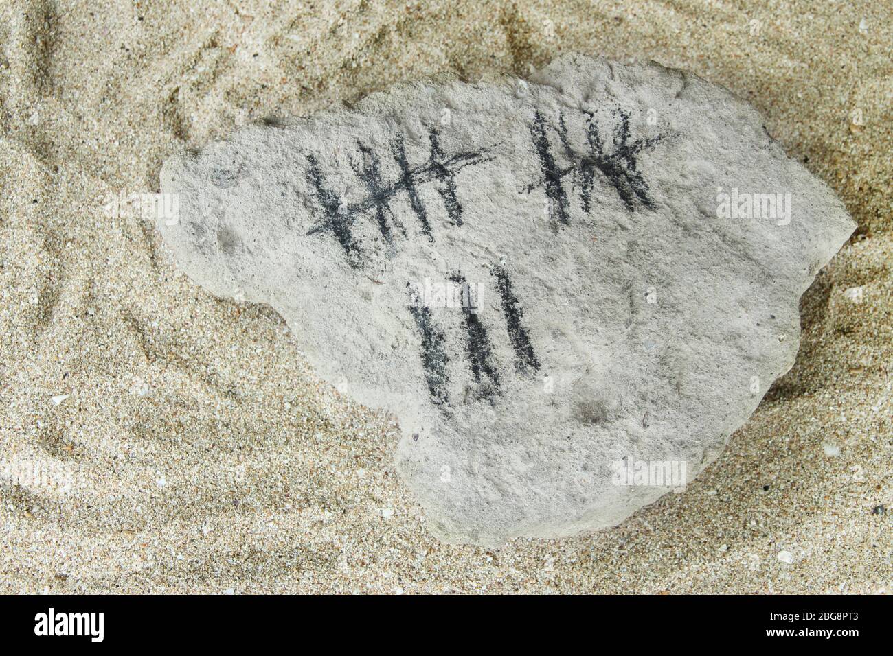 Counting days by drawing sticks on stone on sand background Stock Photo ...