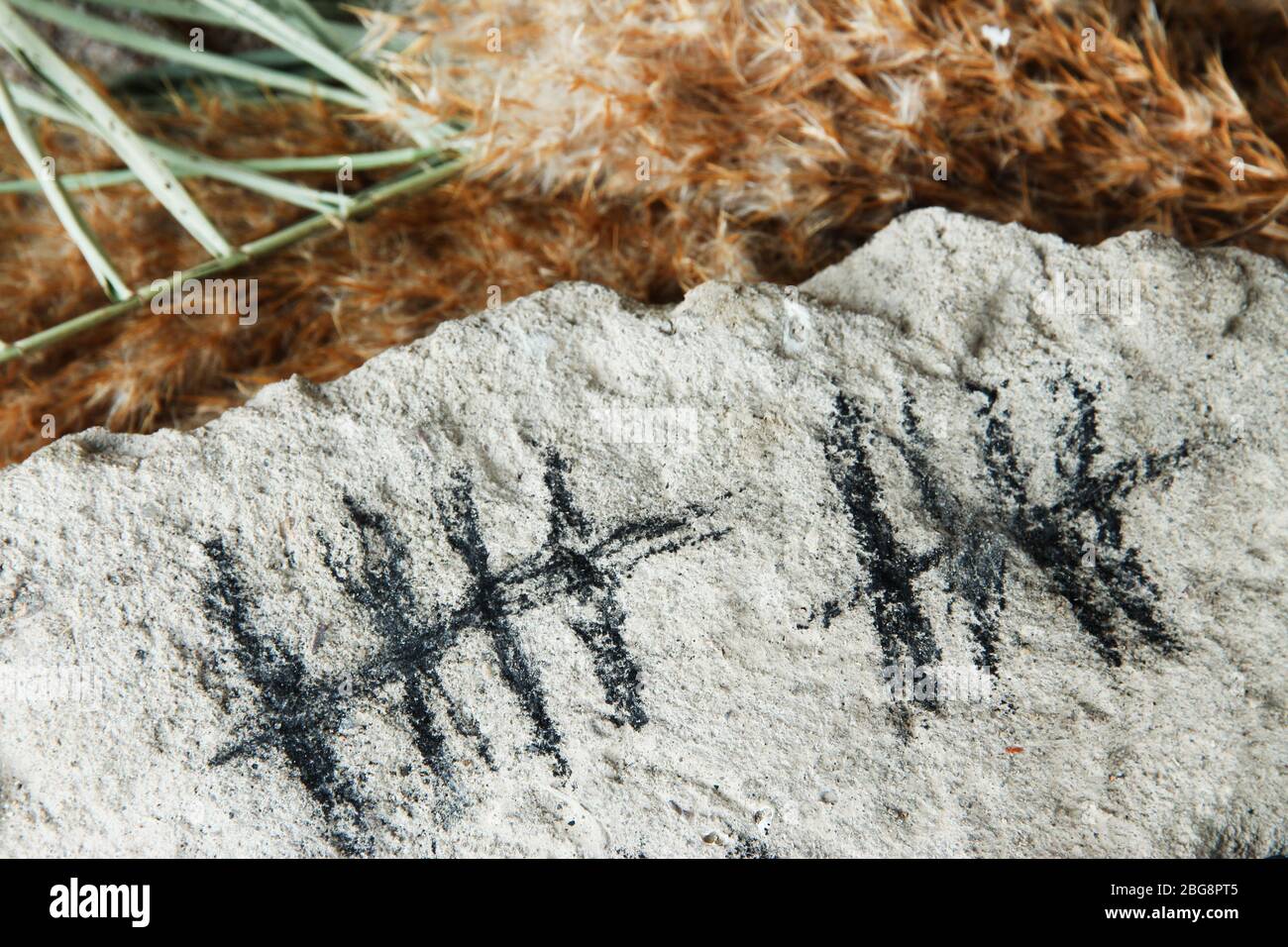 Counting days by drawing sticks on stone close up Stock Photo - Alamy