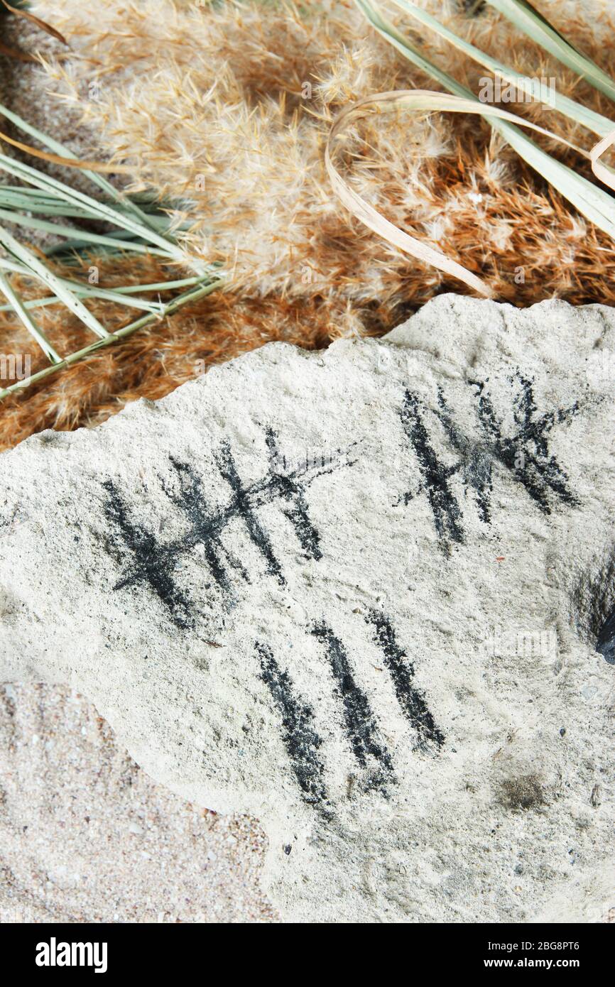 Counting days by drawing sticks on stone close up Stock Photo - Alamy