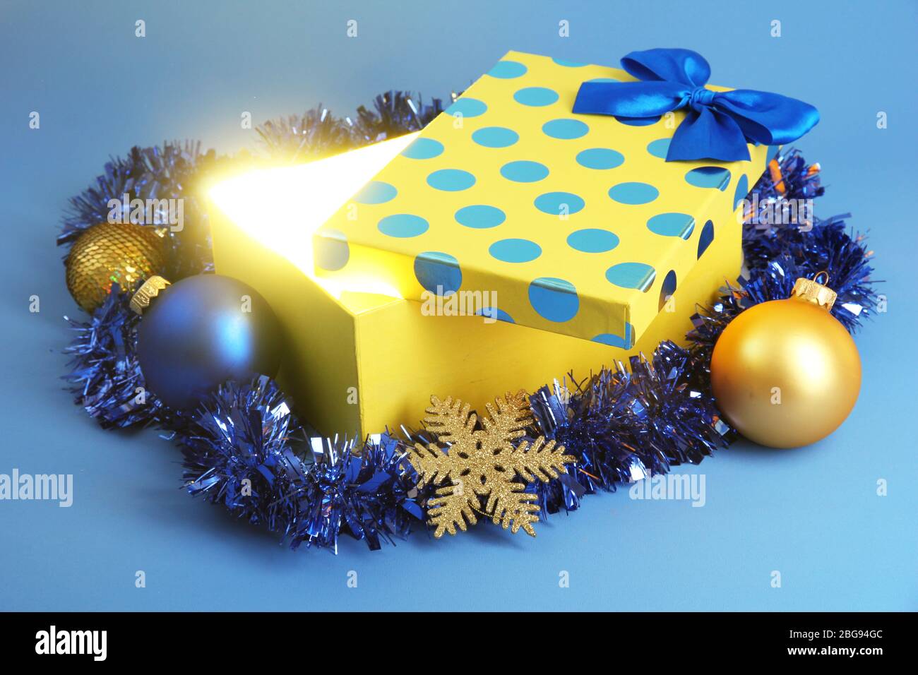 Gift box with bright light on it on blue background Stock Photo - Alamy