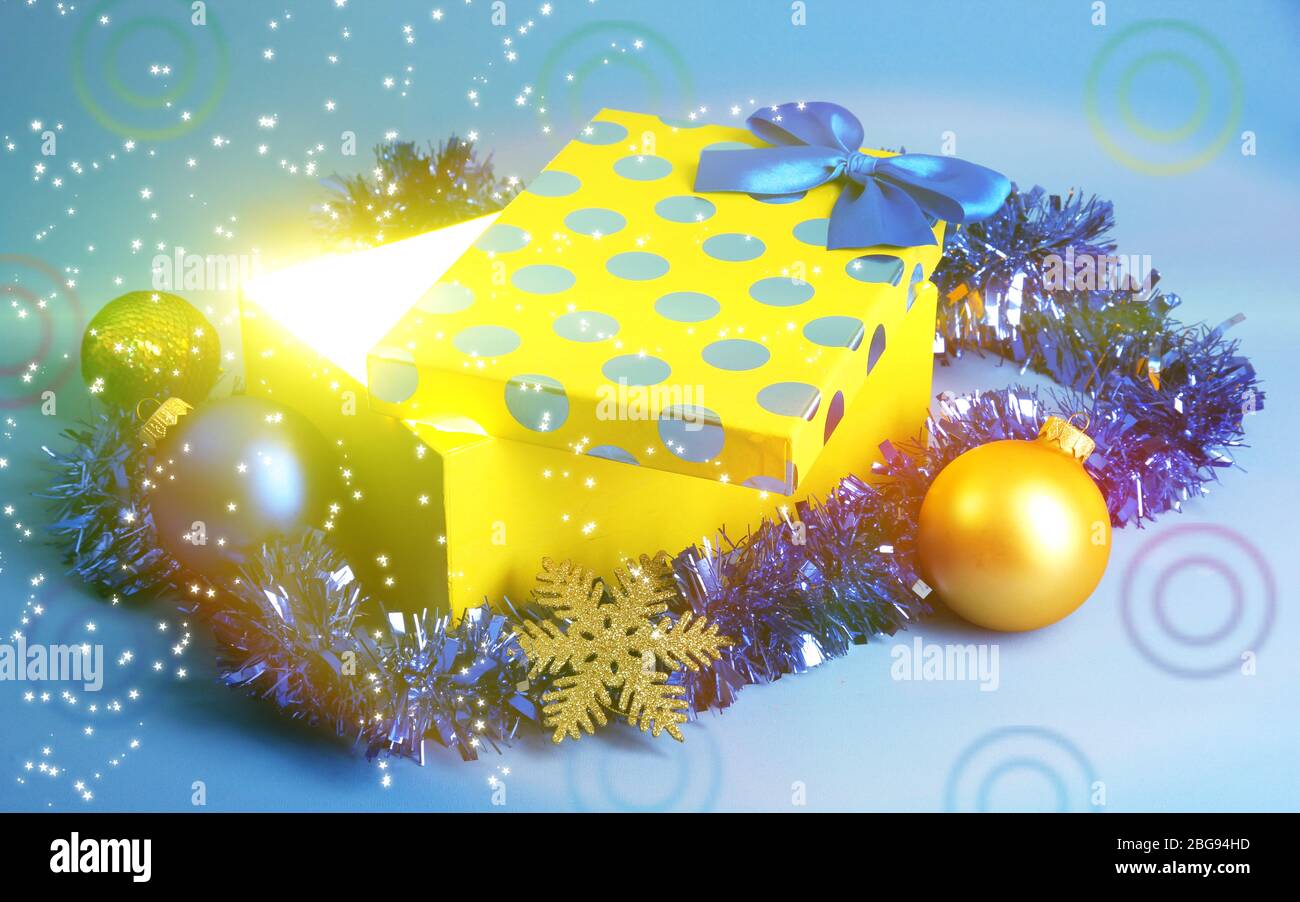 Gift box with bright light on it on blue background Stock Photo - Alamy
