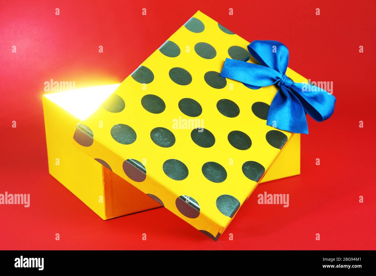 Gift box with bright light on it on red background Stock Photo - Alamy