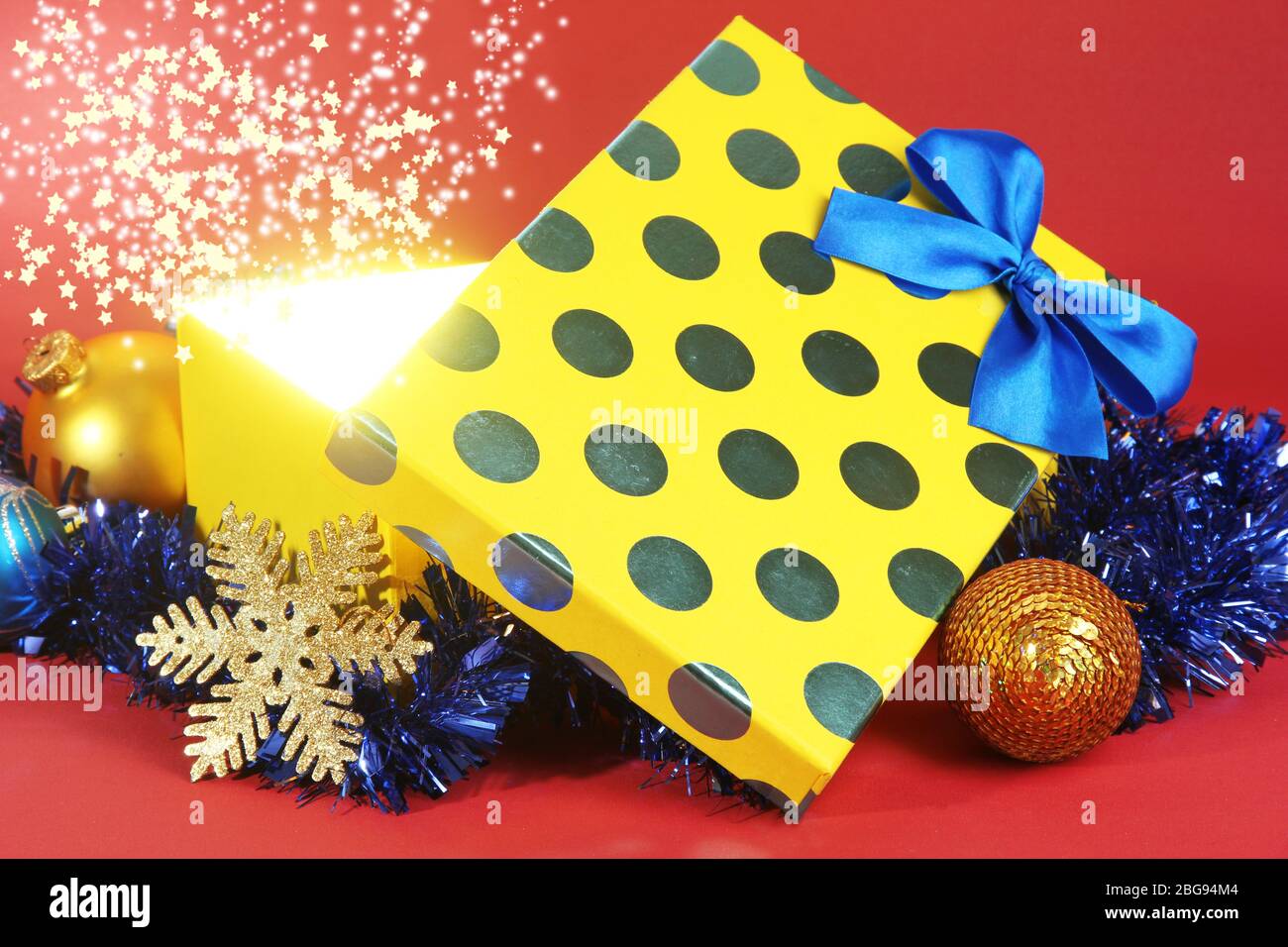 Gift box with bright light on it on red background Stock Photo - Alamy