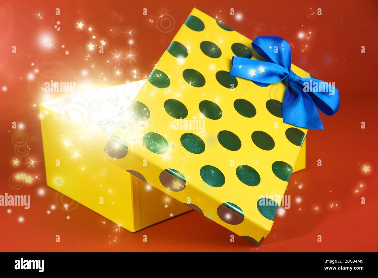 Gift box with bright light on it on red background Stock Photo - Alamy