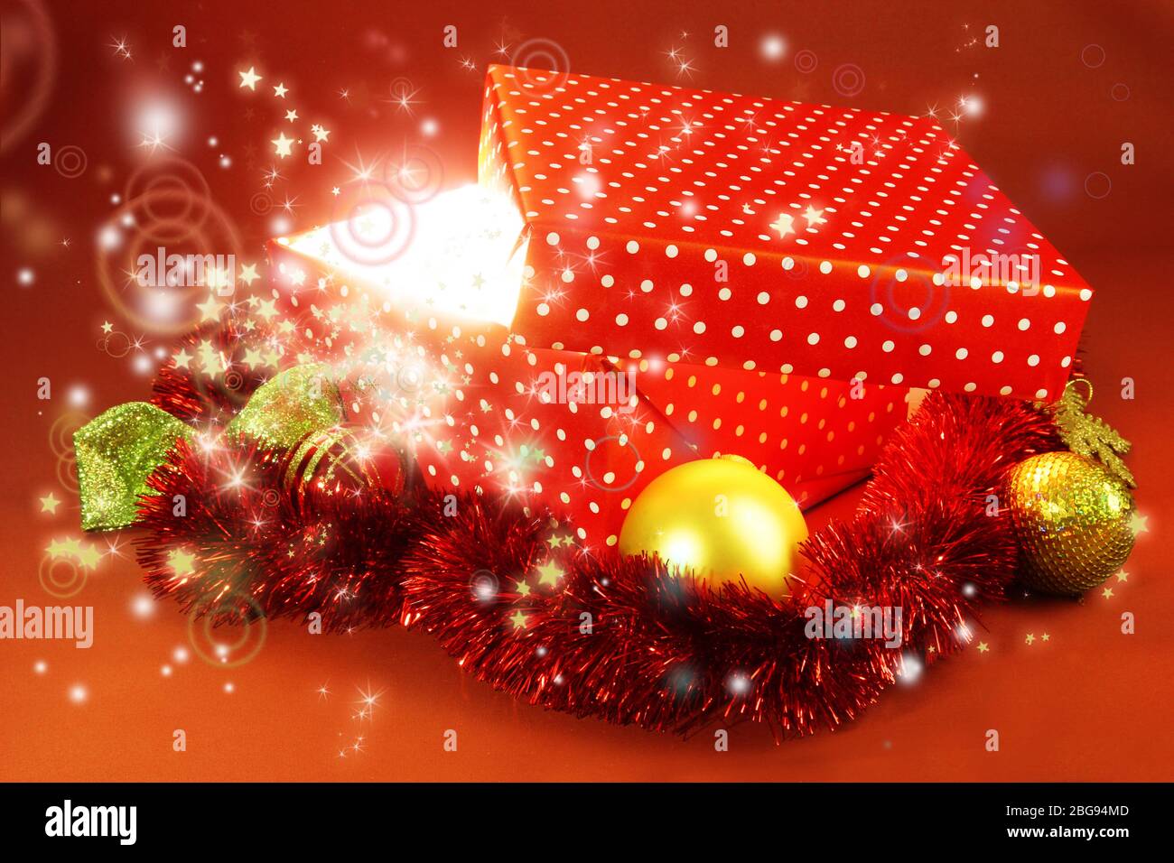 Gift box with bright light on it on red background Stock Photo - Alamy