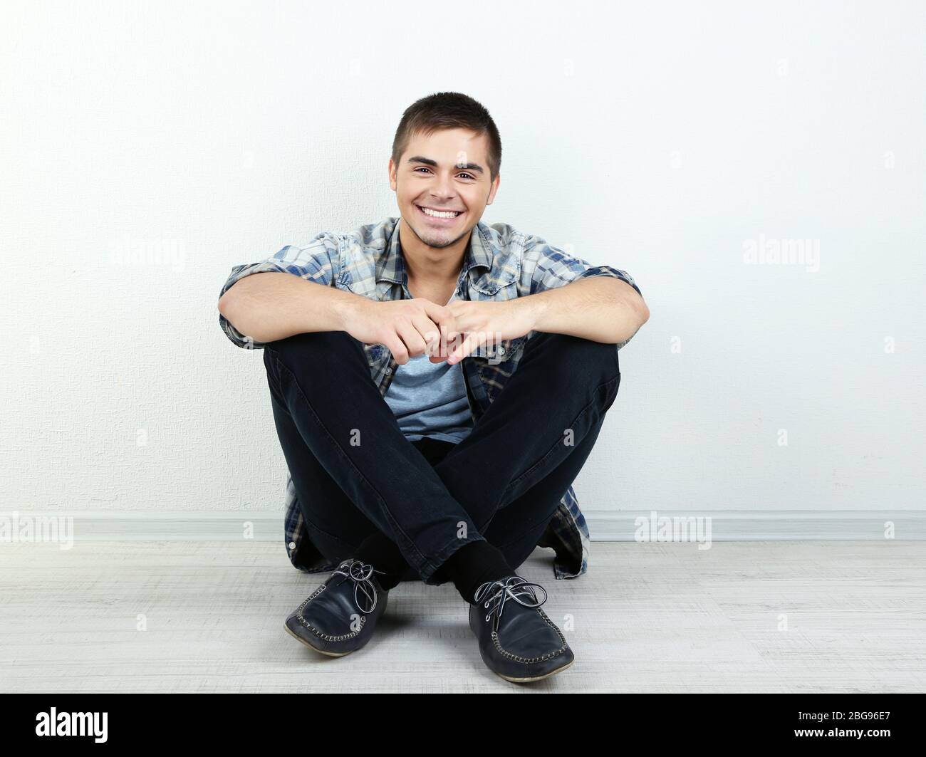 Guy sitting on floor in room Stock Photo - Alamy