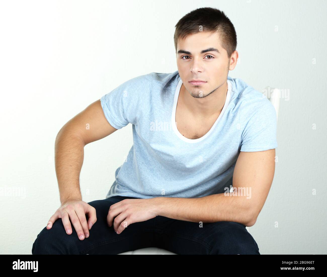Guy sitting on chair in room Stock Photo - Alamy