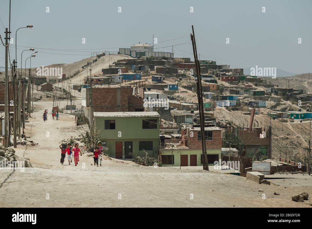 a group of kids running on the dusty dirt road of Manchay, one of the ...