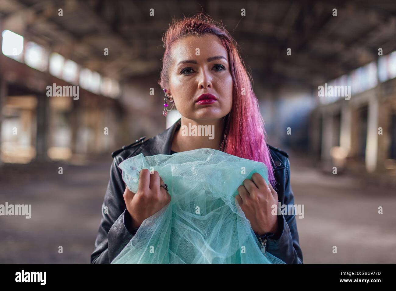 Portrait of a young girl with pink hair standing inside of collapsed ...