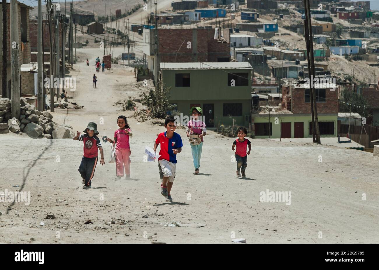 a group of kids running on the dusty dirt road of Manchay, one of the ...