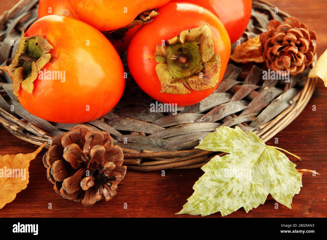 Ripe persimmons with bumps on wicker stand on wooden background Stock ...