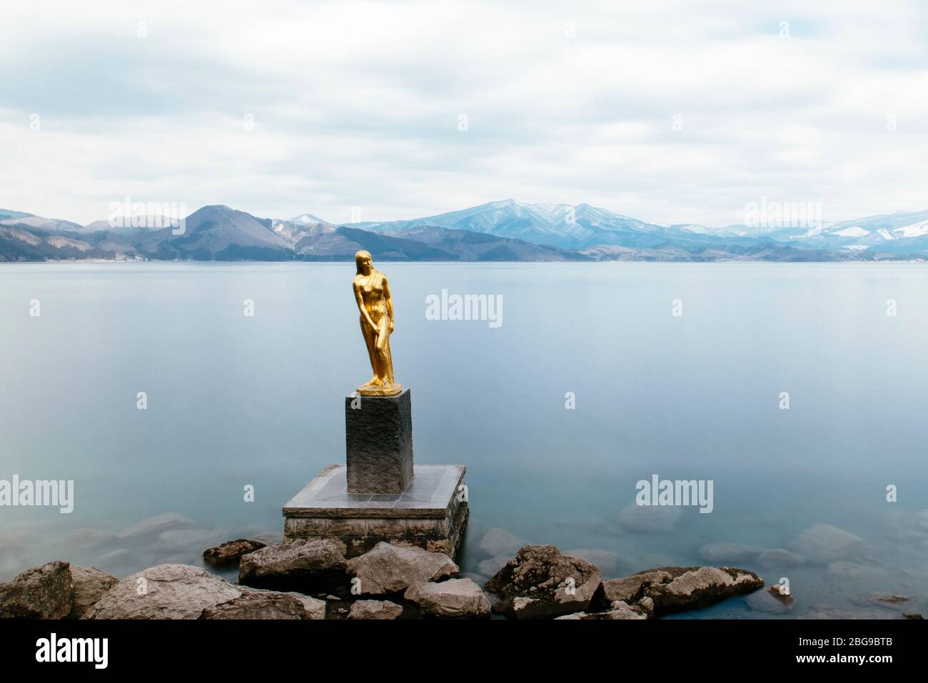A golden statue of Tatsuko stands against the majestic water of Lake ...
