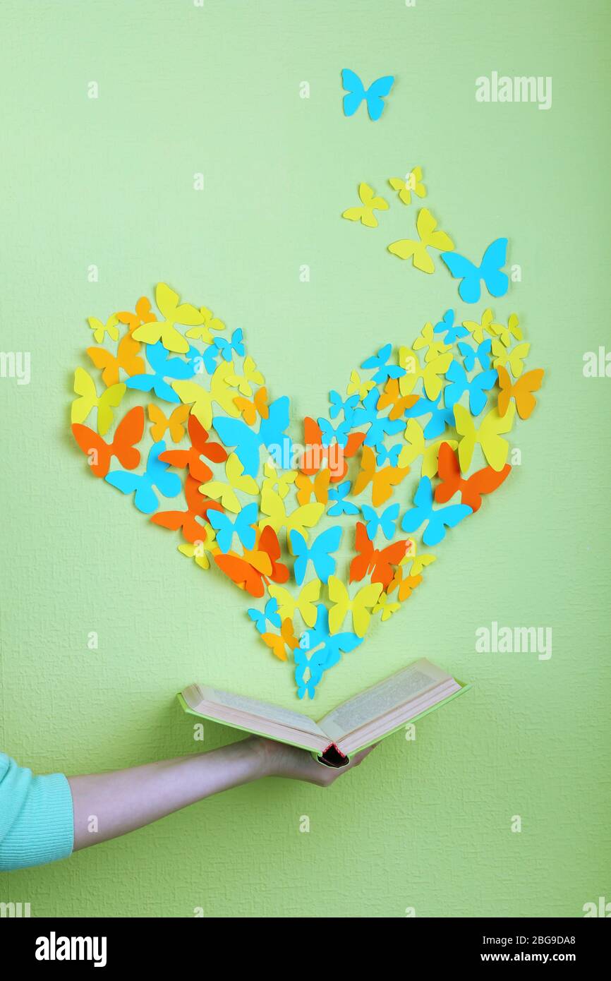 Paper butterflies fly out of book on green wall background Stock Photo ...