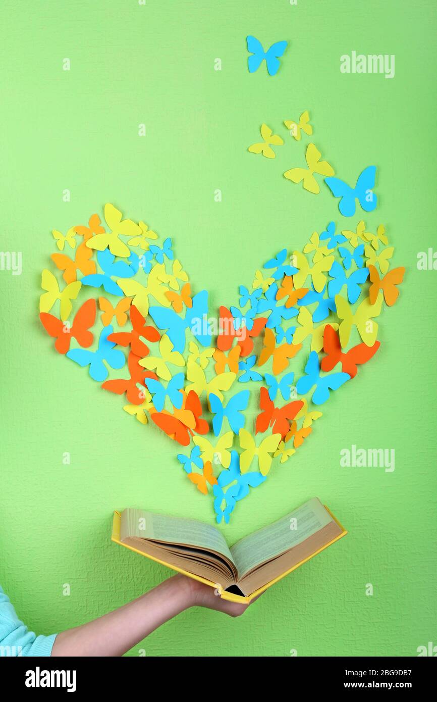 Paper butterflies fly out of book on green wall background Stock Photo ...