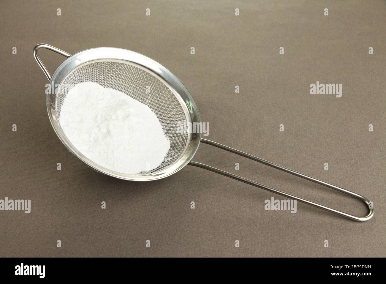 Powdered sugar in metal sieve on grey background Stock Photo - Alamy