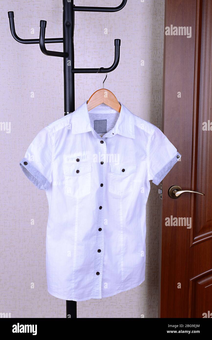 Blouse hanging on hanger near door Stock Photo - Alamy