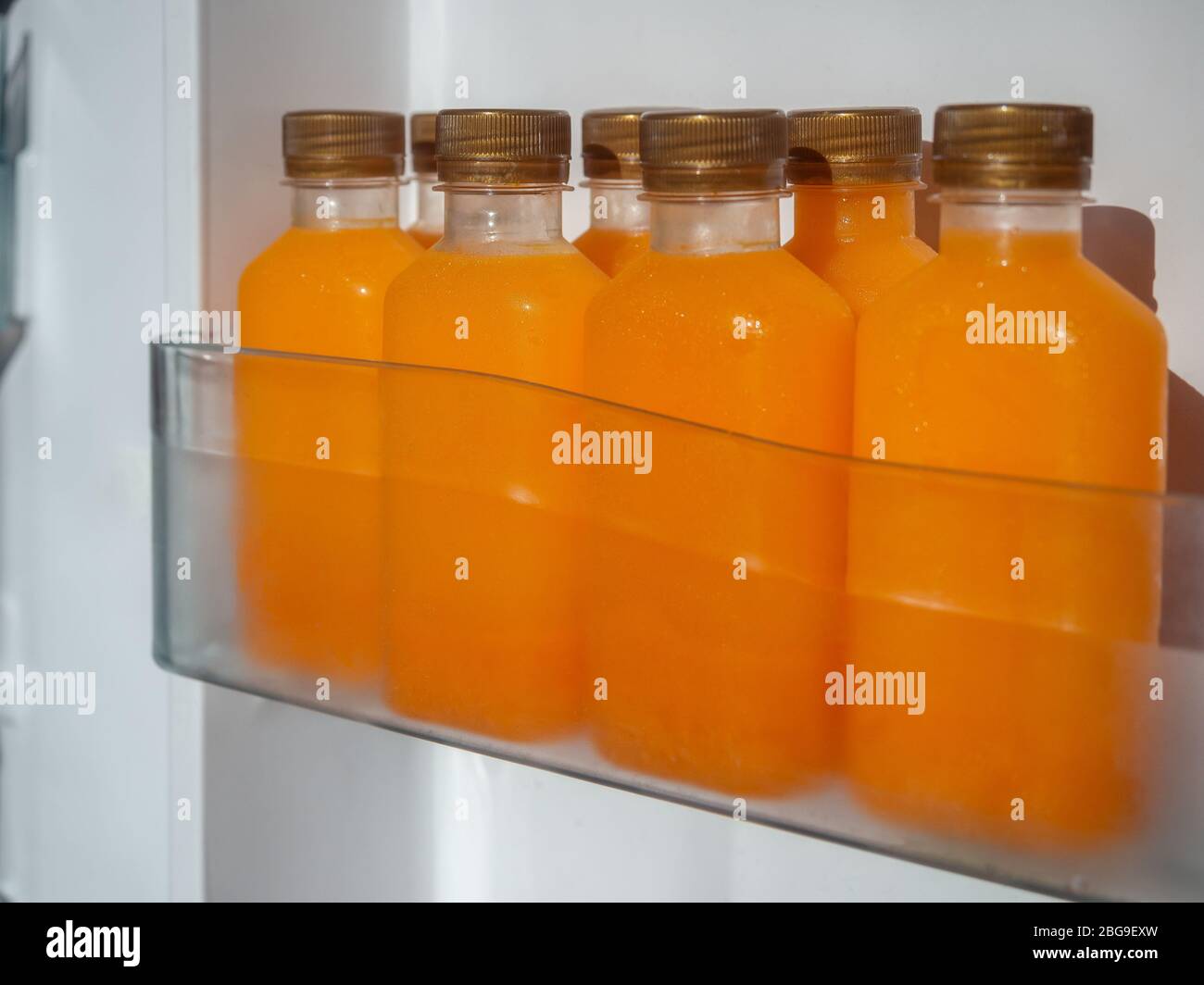 Close-up orange juice iced cold in the bottles on shelf in refrigerator ...