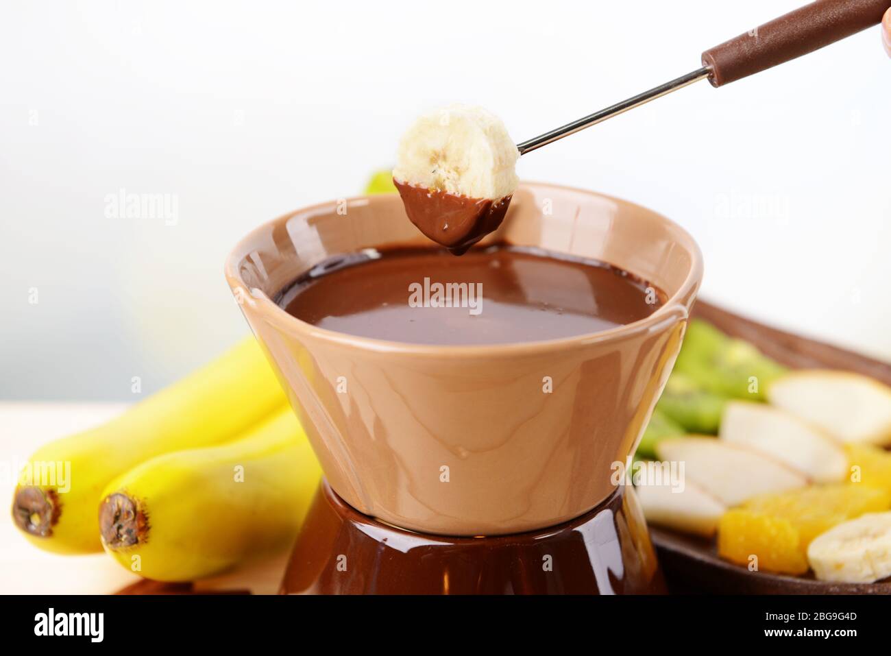 Chocolate fondue with fruits, on wooden table, on light background ...