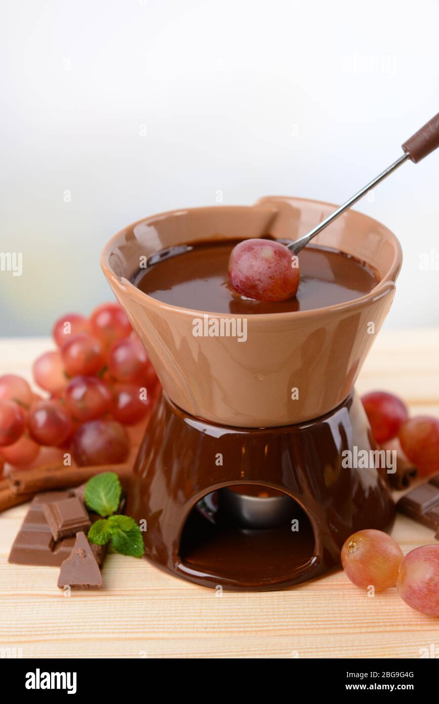 Chocolate fondue with fruits, on wooden table, on light background ...