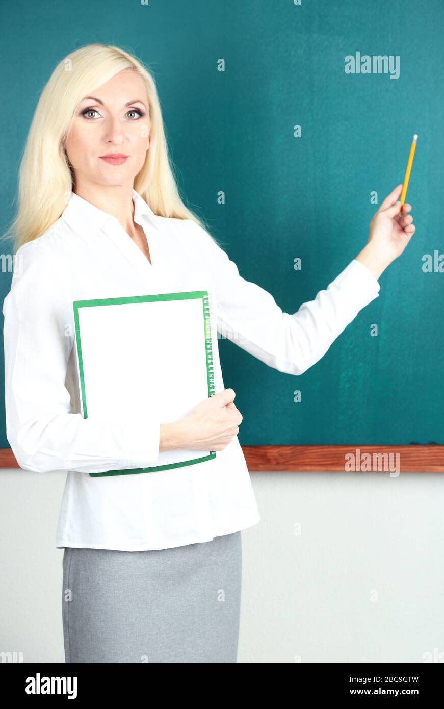 School teacher near blackboard with folder in classroom Stock Photo - Alamy