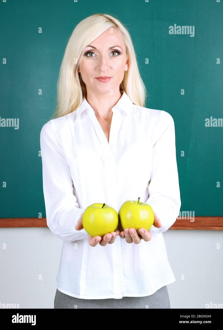 School teacher near blackboard with apples in classroom Stock Photo - Alamy