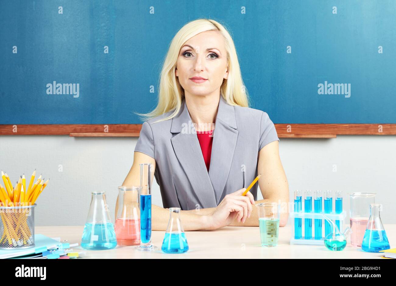 Chemistry teacher sitting at table on blackboard background Stock Photo ...