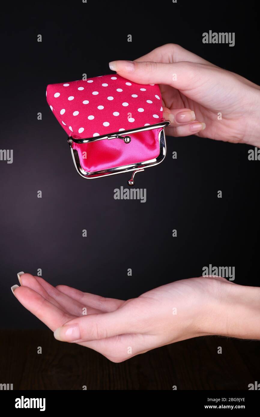 Female hand holding pink purse on black background Stock Photo - Alamy