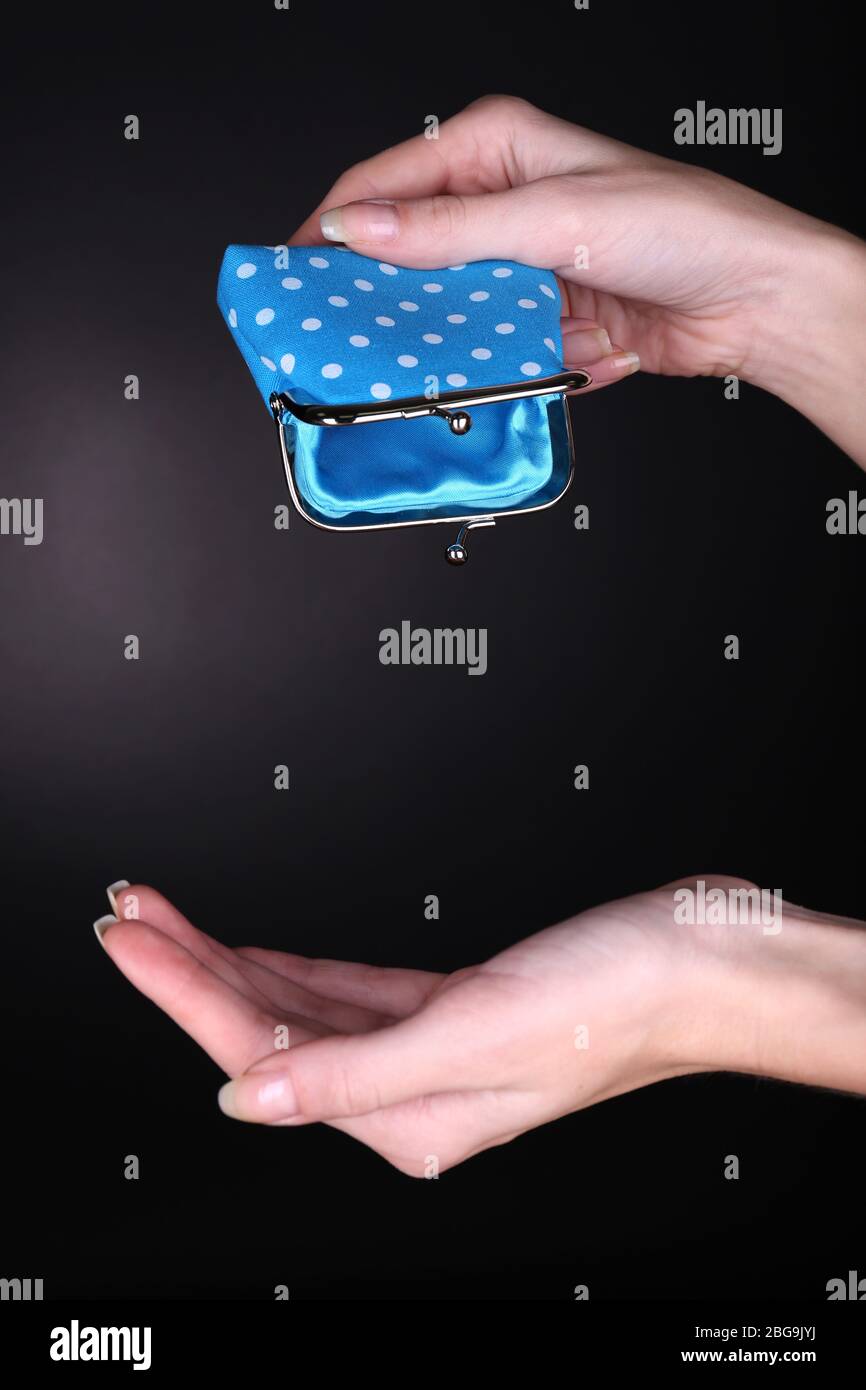 Female hand holding blue purse on black background Stock Photo - Alamy