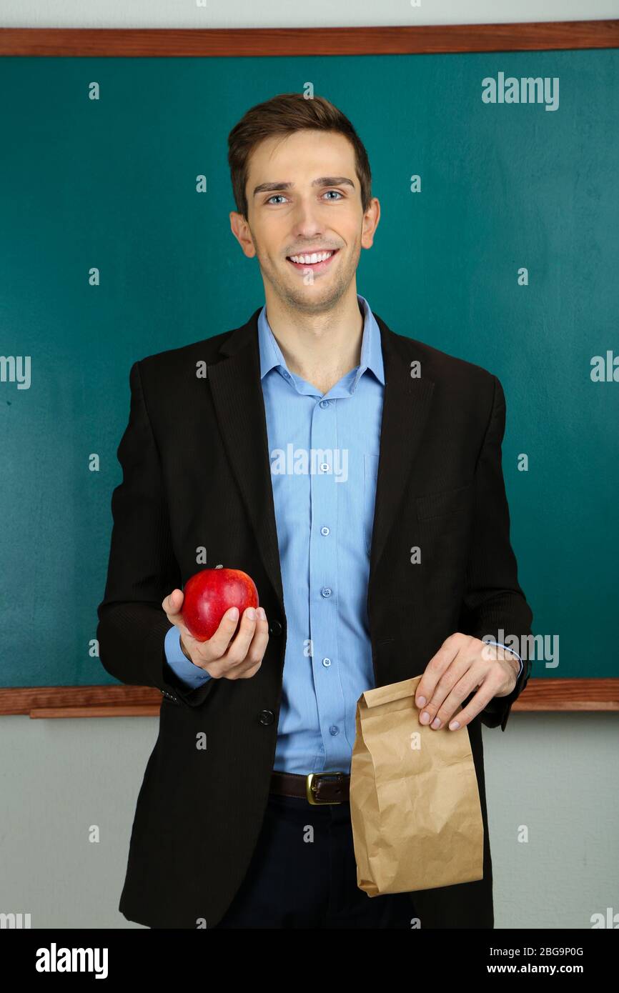 Young teacher with school lunch near chalkboard in school classroom ...