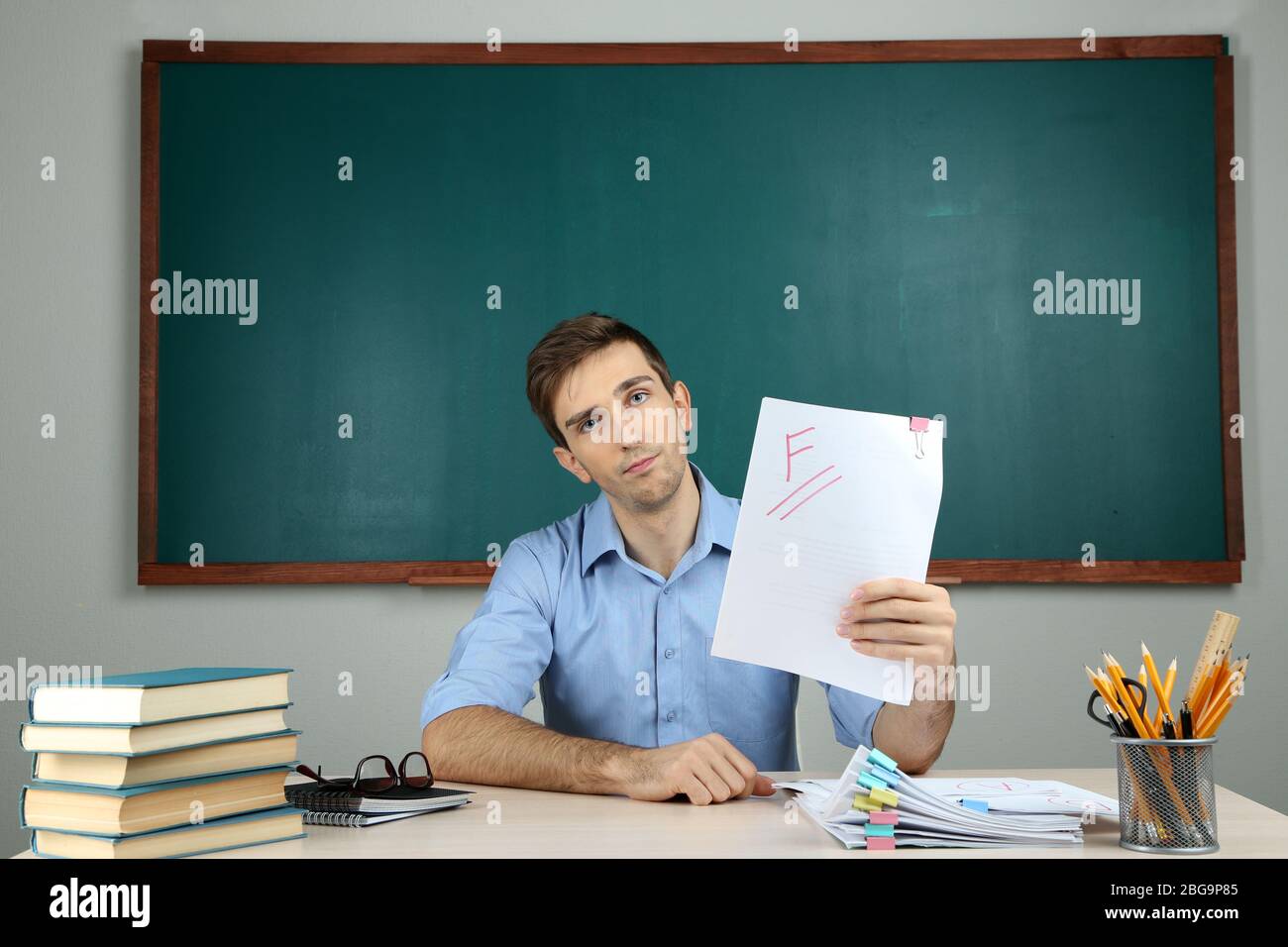 Young teacher sitting in school classroom Stock Photo - Alamy